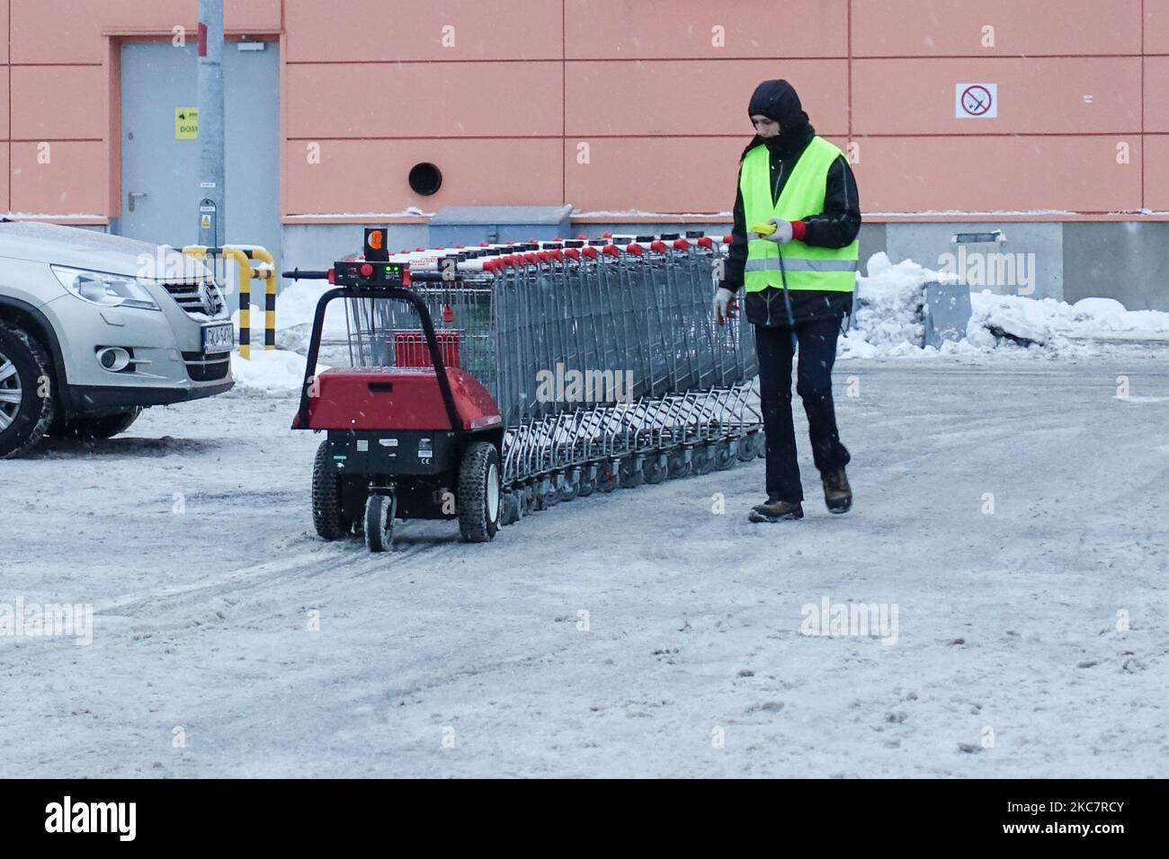 Shopping mall, supermarket worker moving shopping carts with an ...