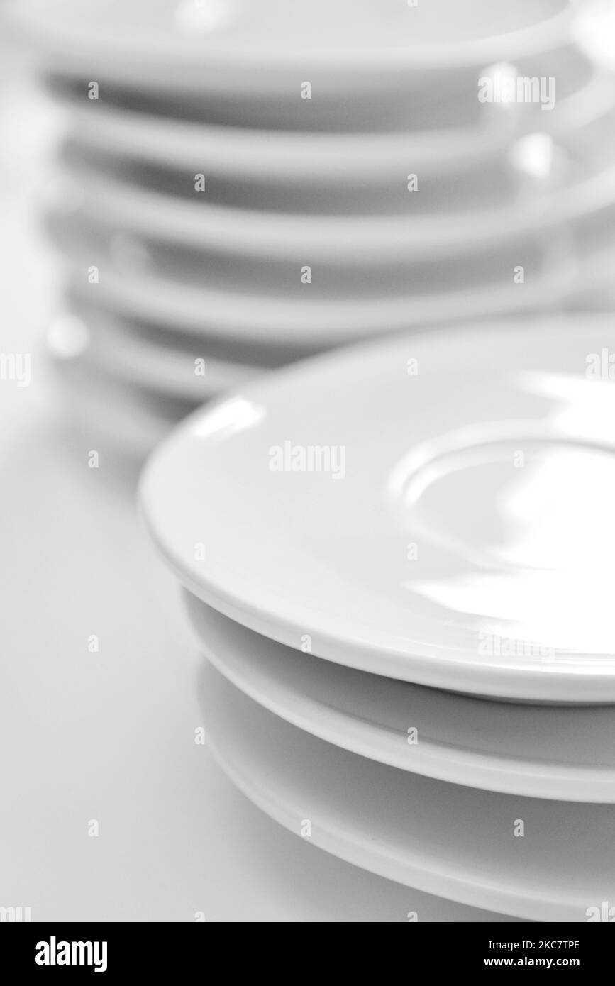 A vertical shot of a stack of white plates put on a white surface on ...