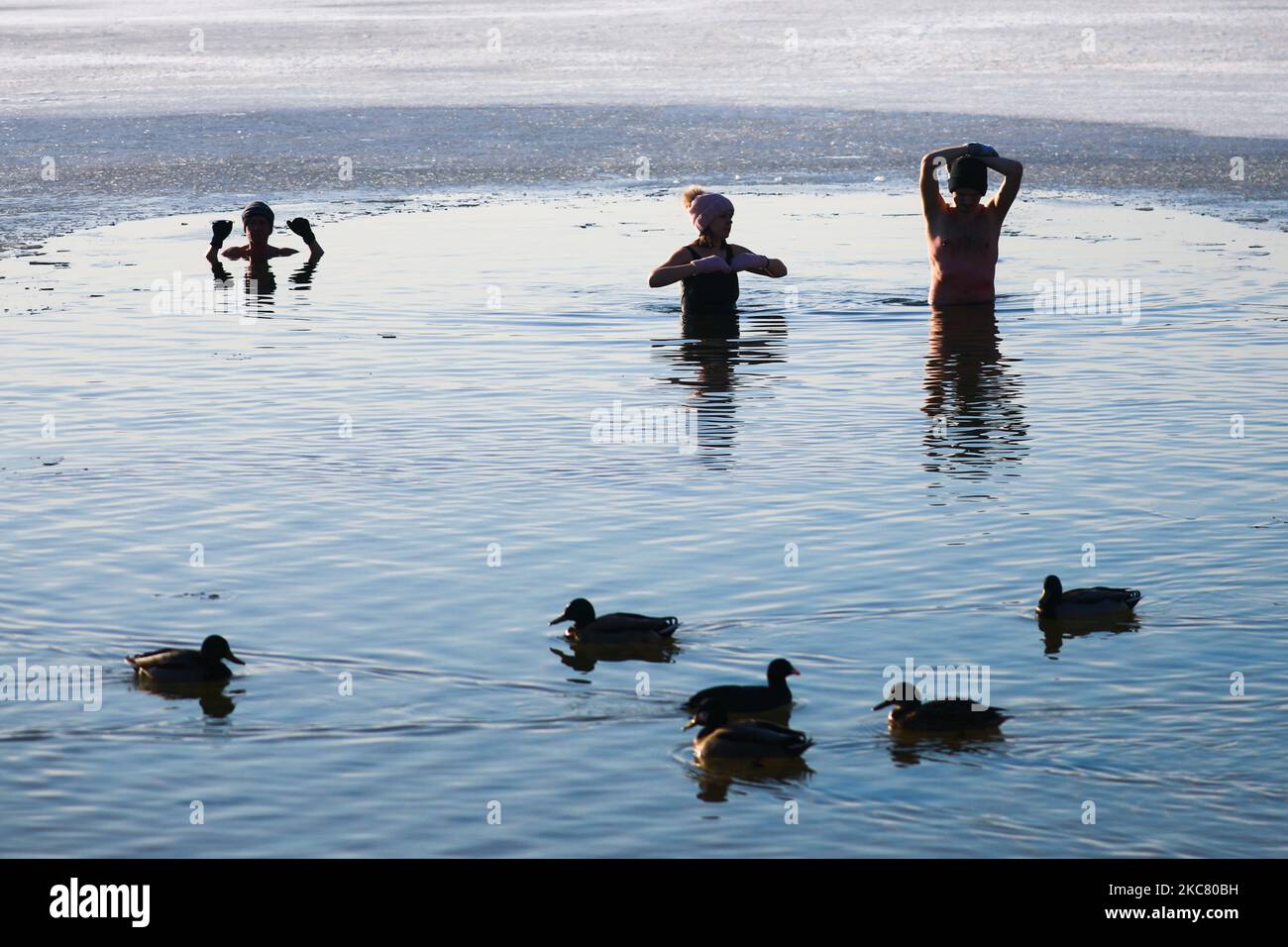 Winter swimmers take a dip in cold water of partly frozen Bagry lake in ...