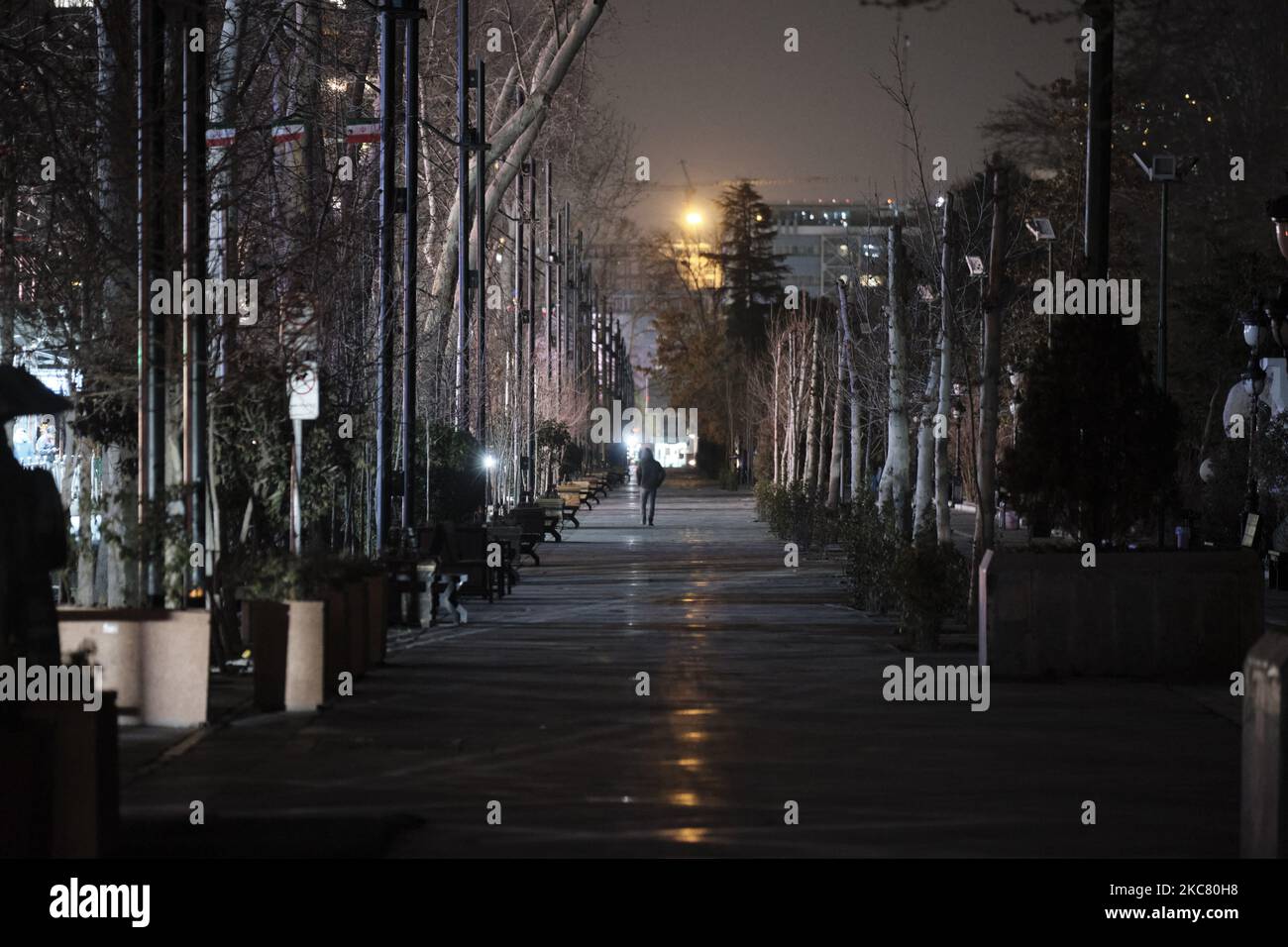 An Iranian man walks along a street-side while power blackouts in ...