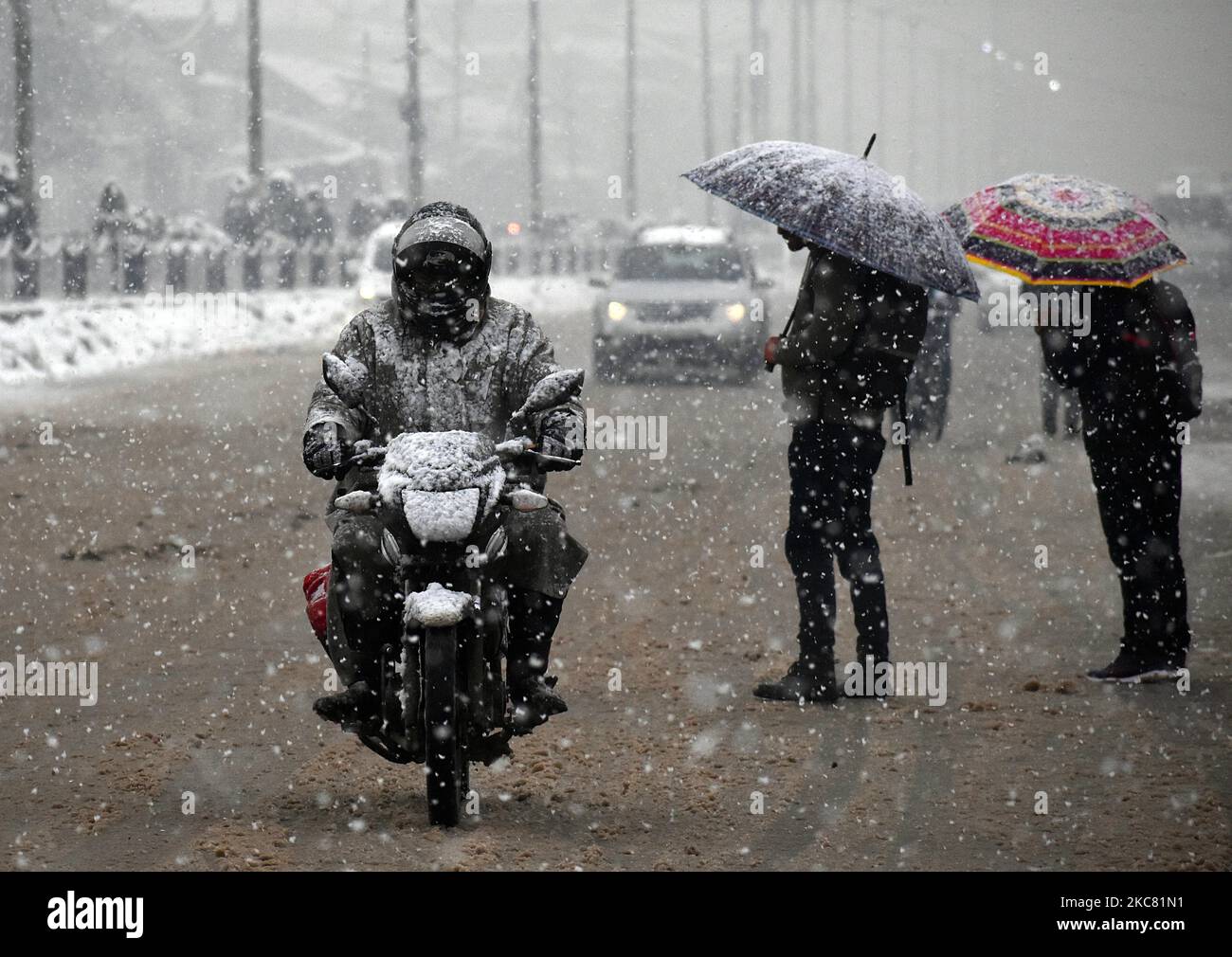 A man rides a bike as it snows in Srinagar,Kashmir on January 23, 2021 ...