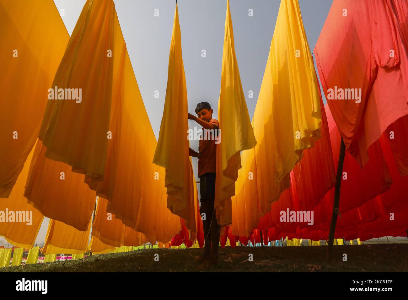 A man collects dry fabric after a dyeing process at a factory in ...