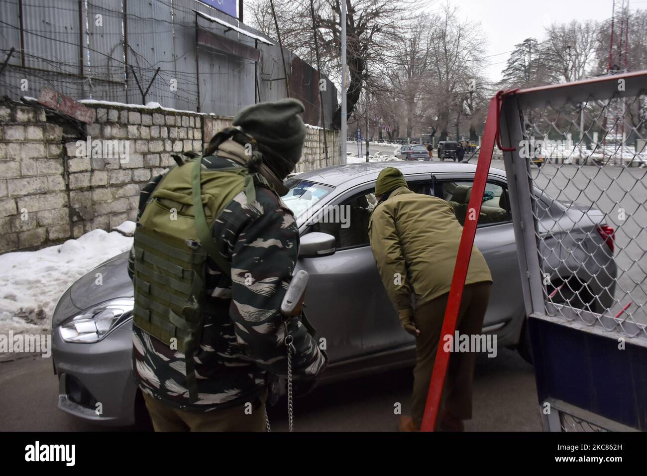 Indian police forces stops a civilian vehicle near a road block ahead ...