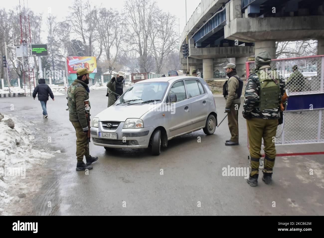 Indian police forces stops a civilian vehicle near a road block ahead ...