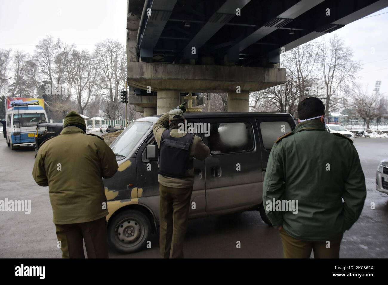 Indian police forces stops a civilian vehicle near a road block ahead ...