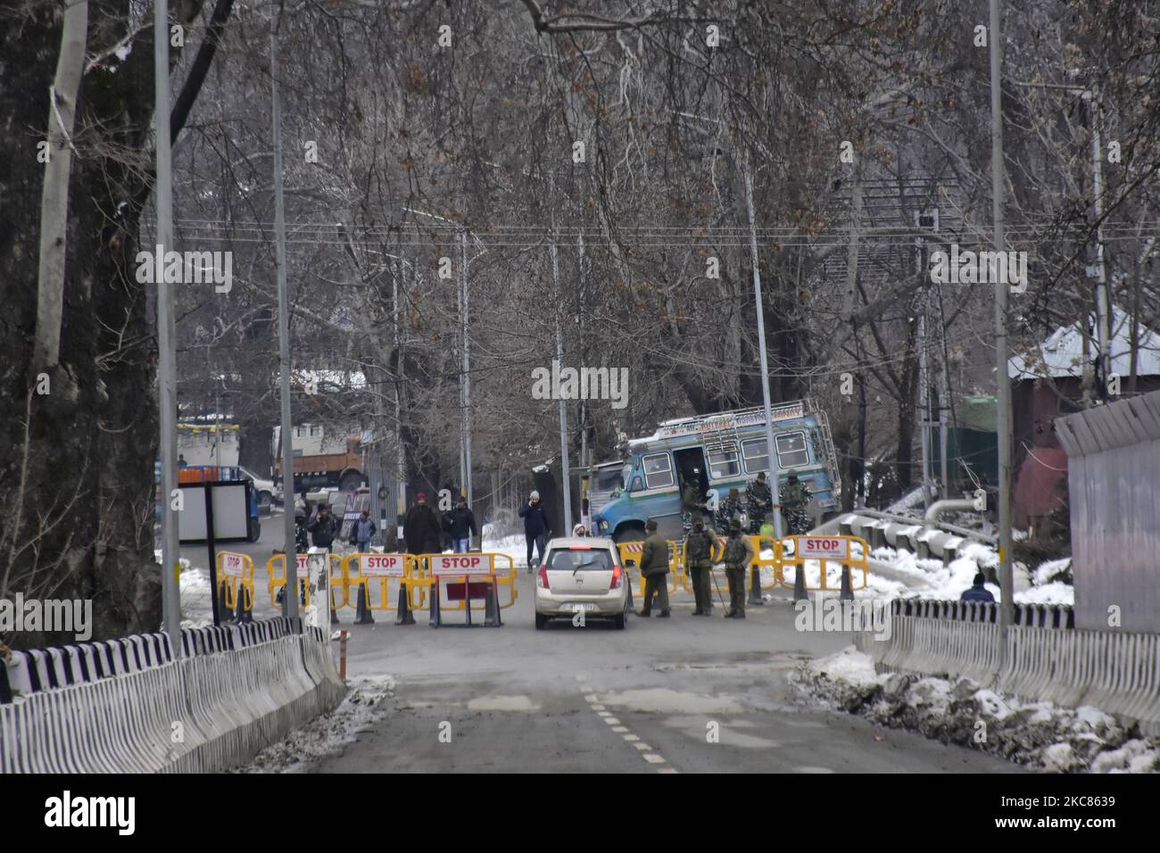 Indian police forces stops a civilian vehicle near a road block ahead ...