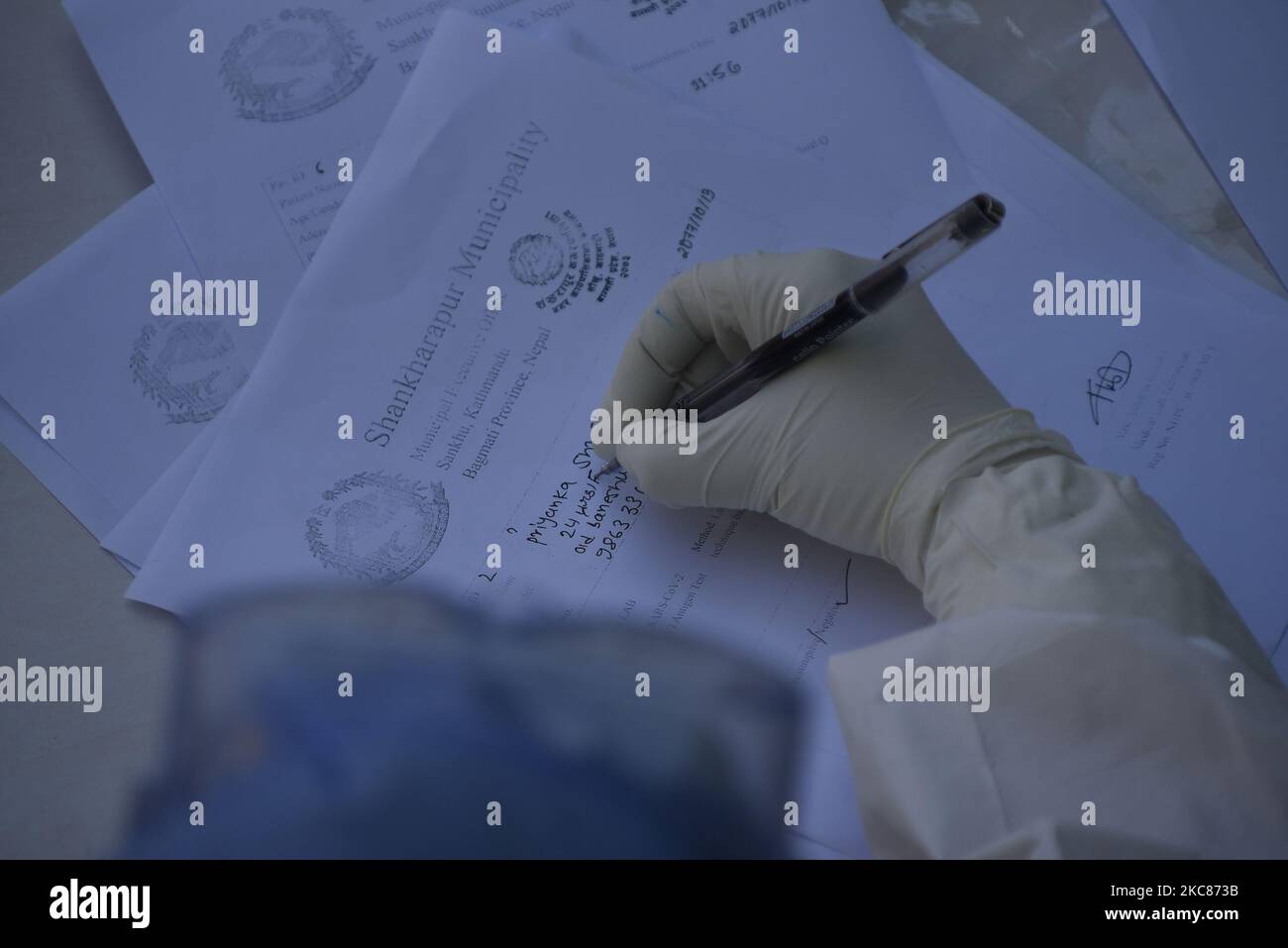 A Nepalese Health personnel fill form before collect mouth swab sample ...