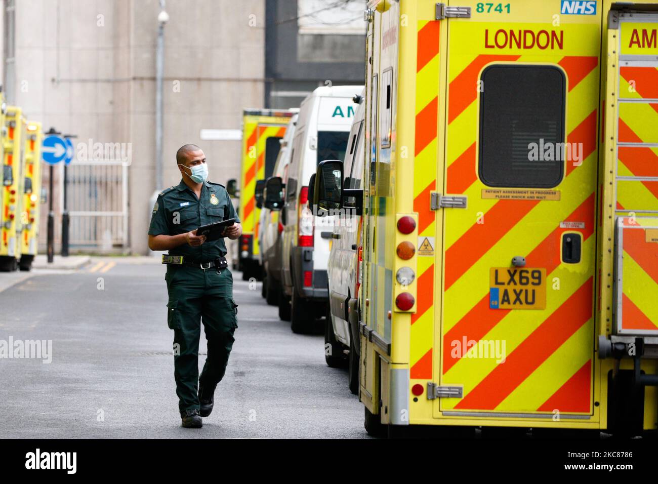 A paramedic walks beside ambulances outside the emergency department of ...