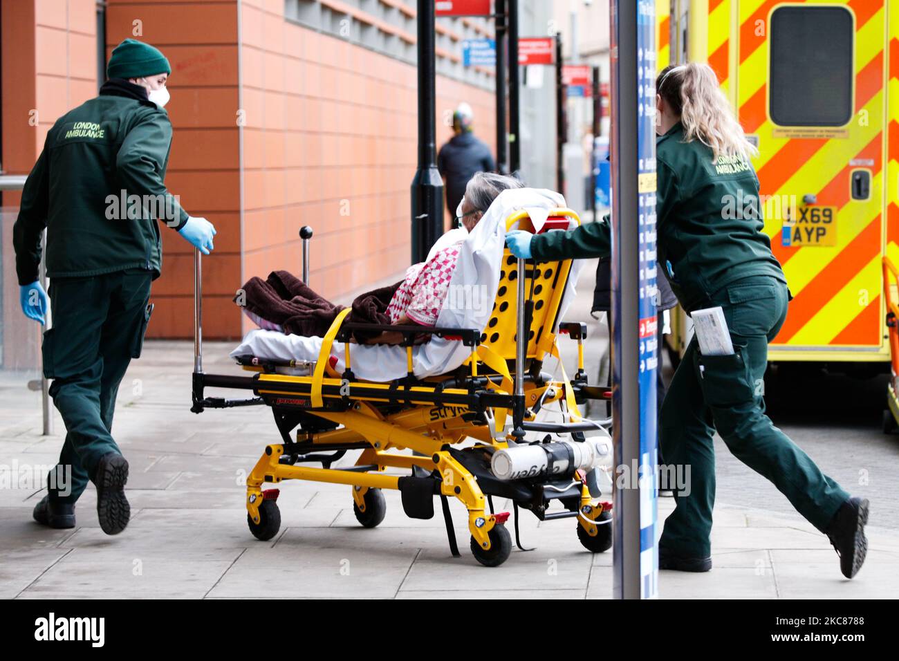 Paramedics wheel a patient wearing an oxygen mask into the emergency ...
