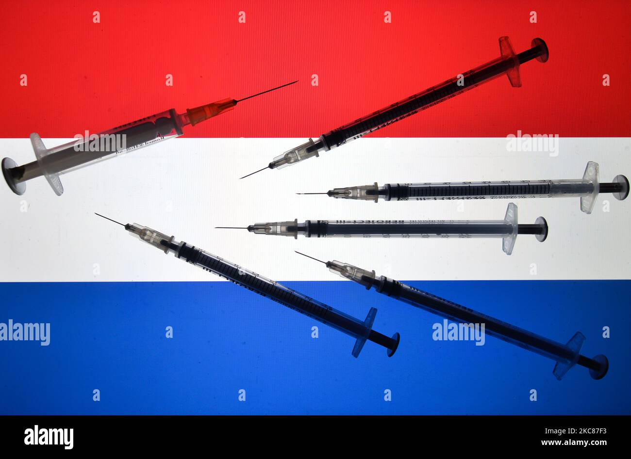 An illustrative image of medical syringes in front of a flag of ...