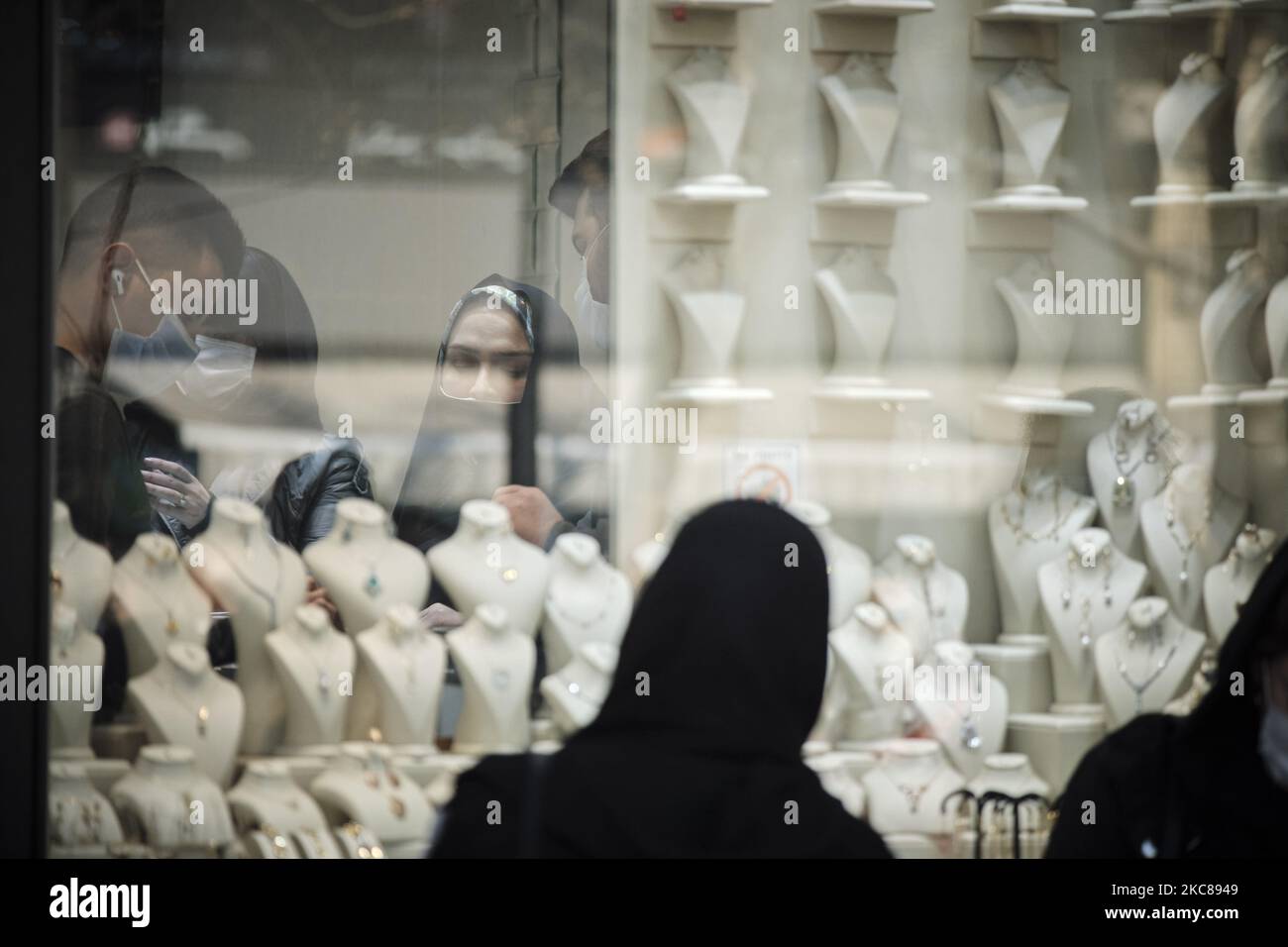 An Iranian Veiled Woman Looks On As She Sits At A Gold And Jewelry Shop