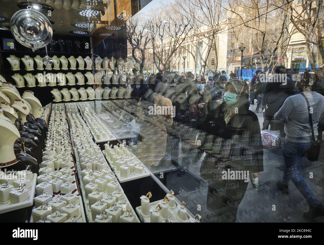 An Iranian veiled woman wearing a protective face mask looks on a gold ...