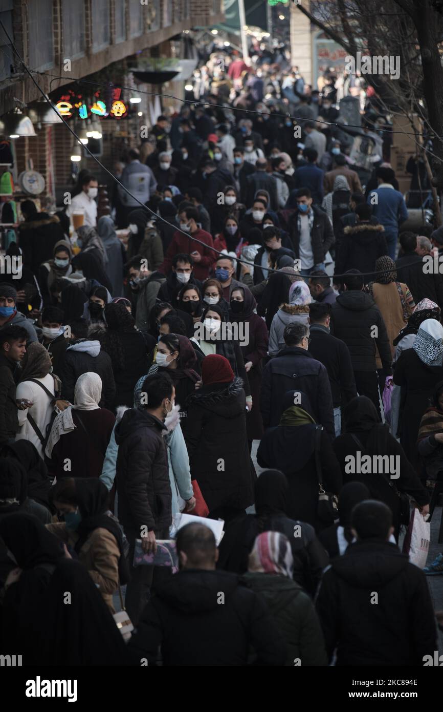 Iranian people wearing protective face masks walk along a street-side ...