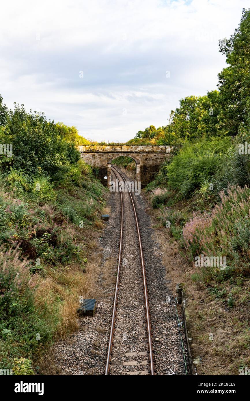 A vertical shot of railway tracks going under a stone bridge in North ...