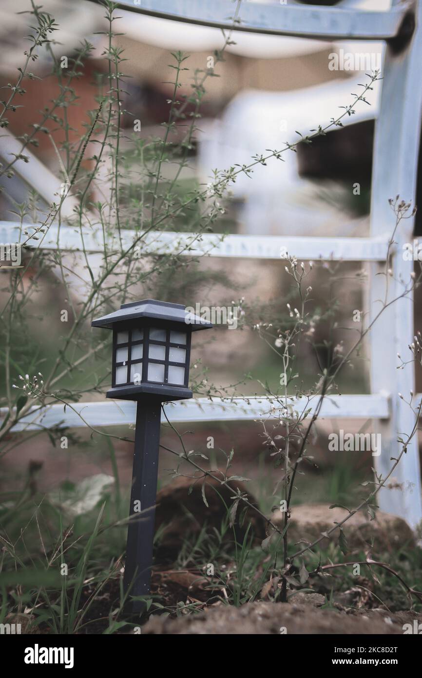 A vertical of a small solar power pathway lamp beside a fence in ...