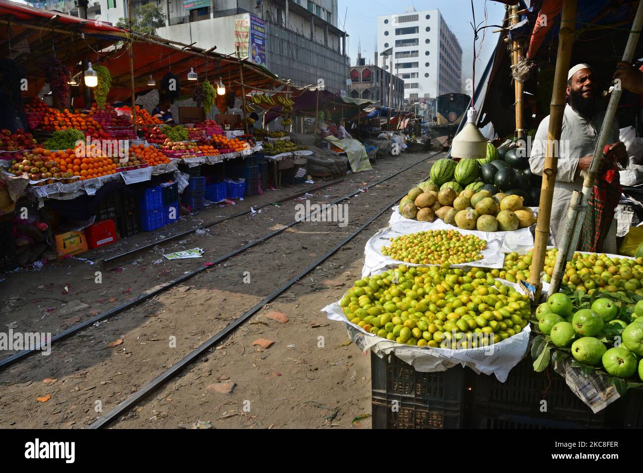 A Bangladeshi vendor sells fruits along the railway track in Dhaka ...