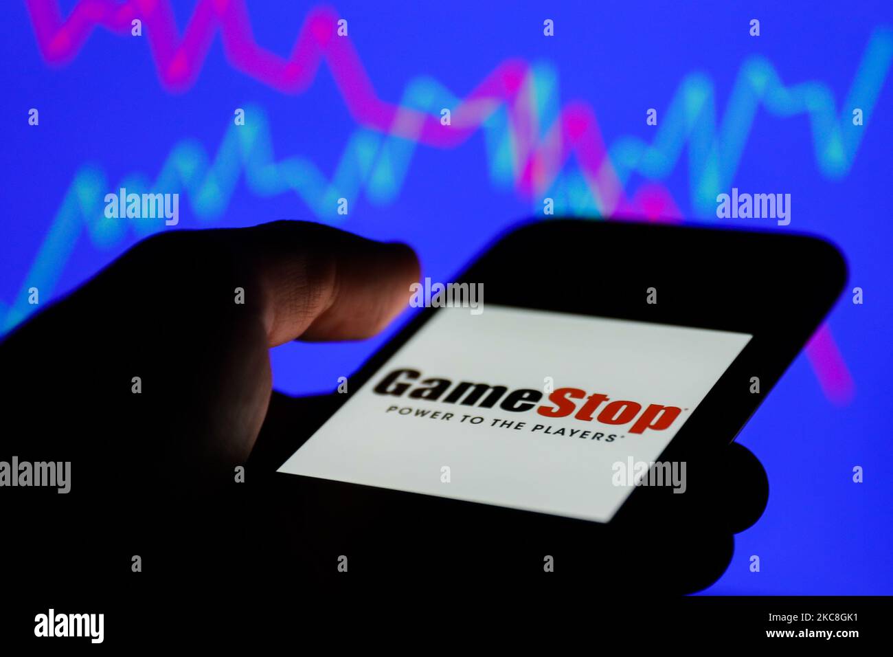 GameStop logo displayed on a phone screen and a illustrative stock ...