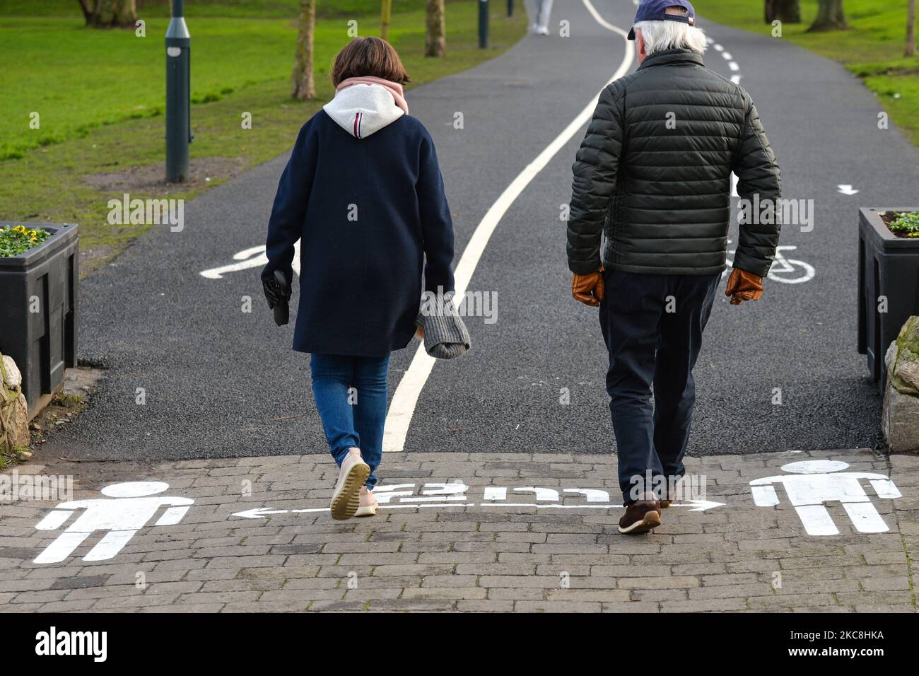 A couple walking by a social distancing sign at the entrance to ...