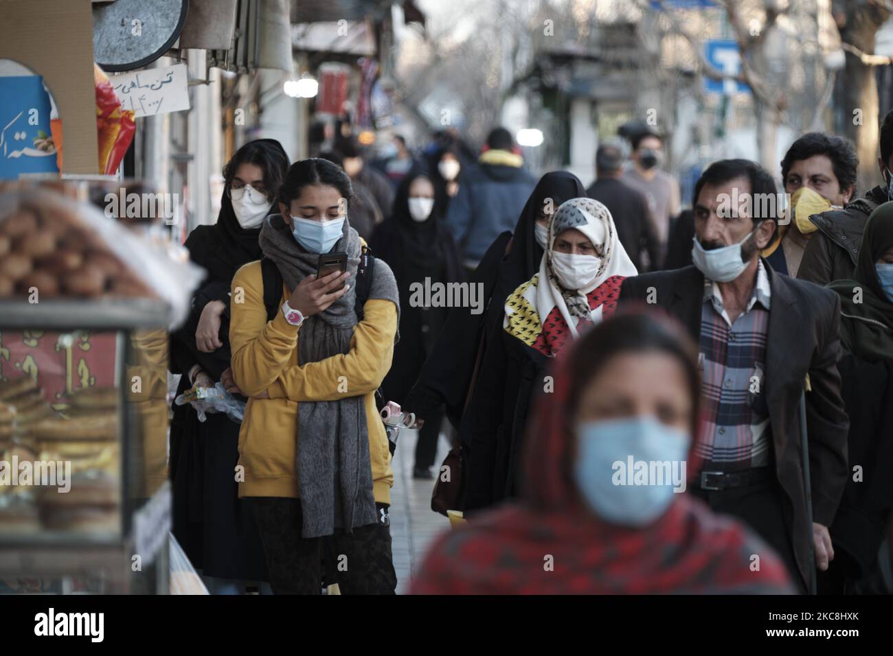 An Iranian woman wearing a protective face mask uses her smartphone ...