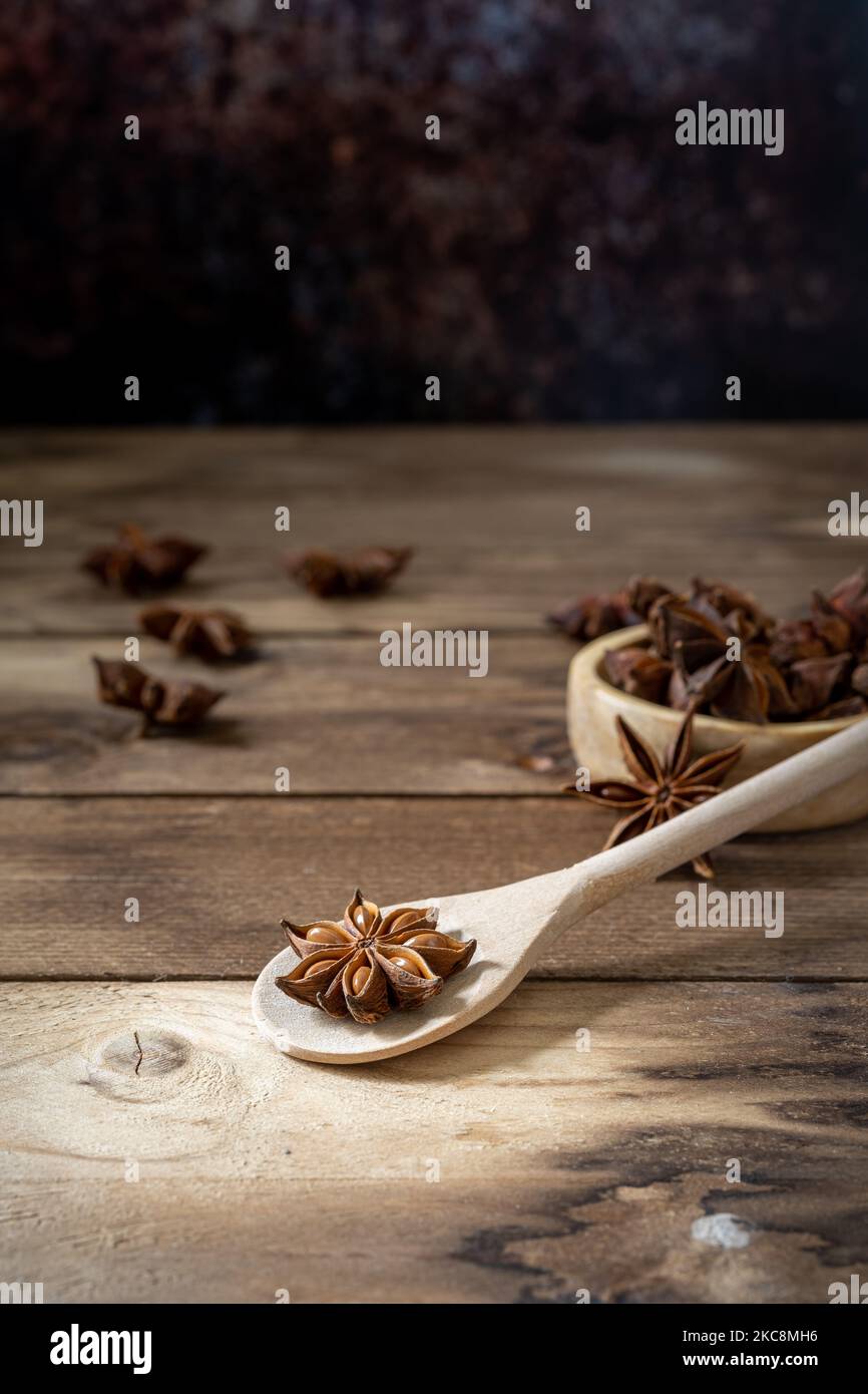 Anise stars (Illicium verum ) in wooden spoon and wooden bowl on dark ...