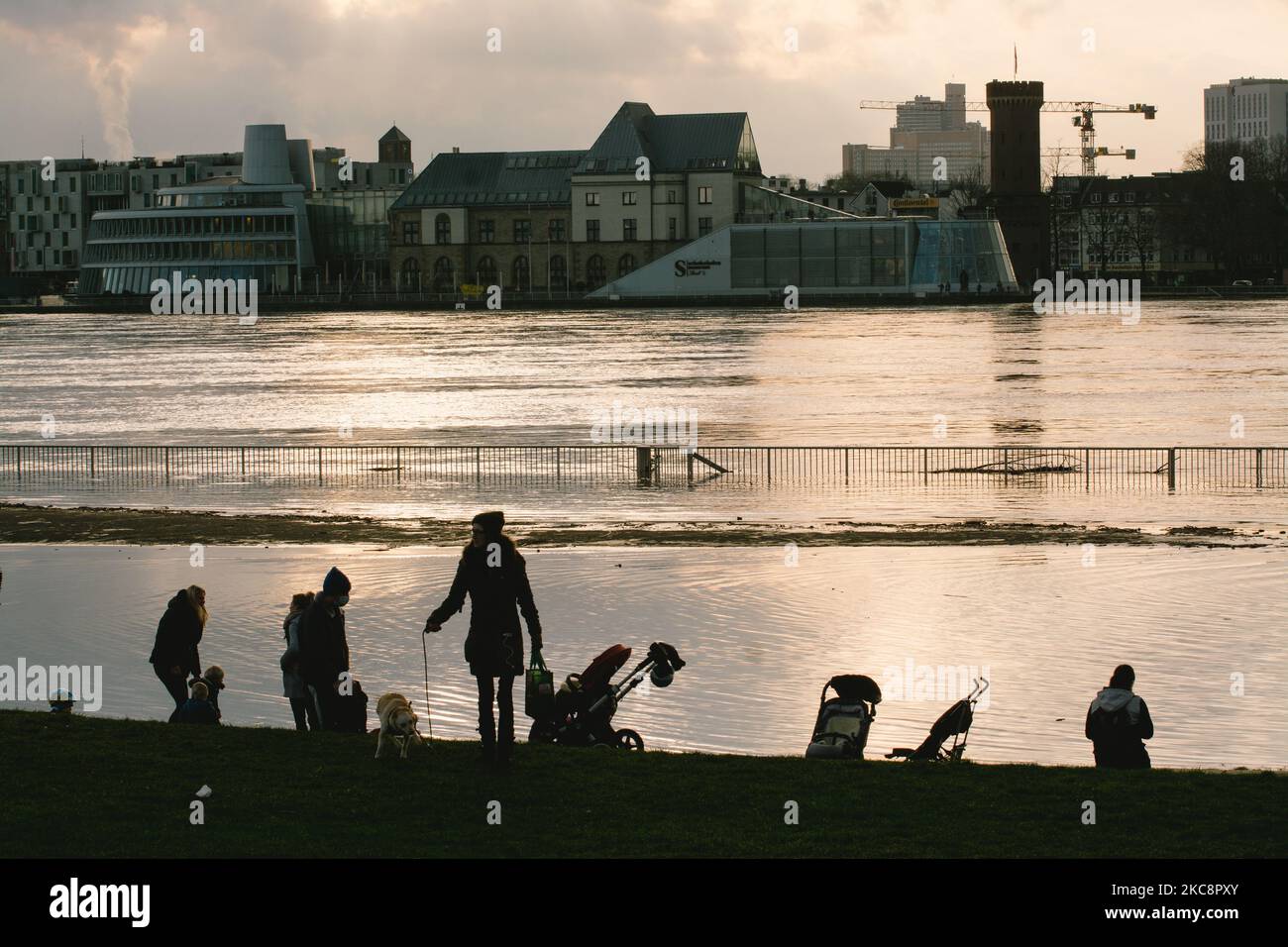 people enjoy sunset and sit around the flooded area as Rhine river ...