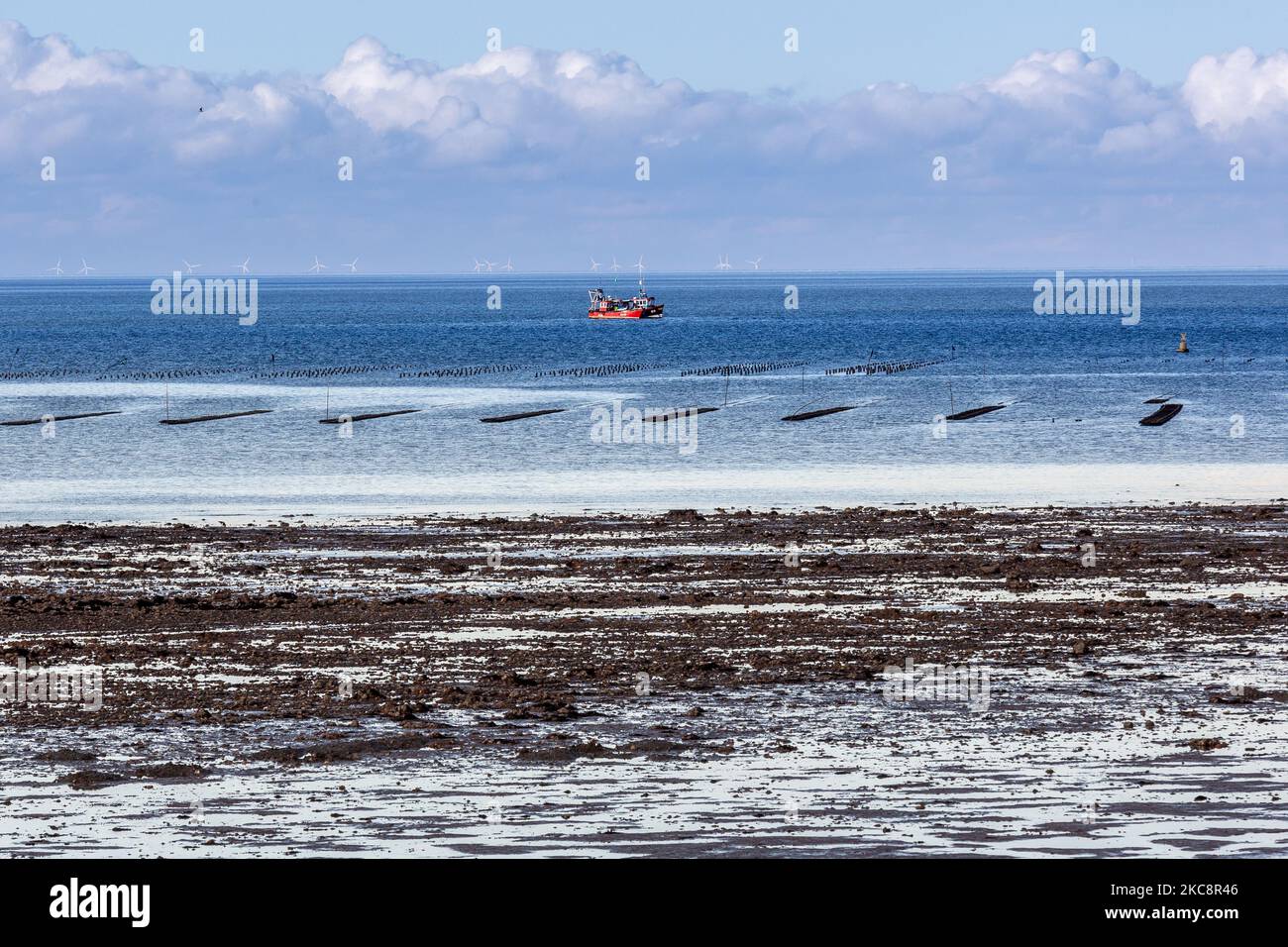 Fishing vessel in front of oyster trestles in front of windmills on the ...