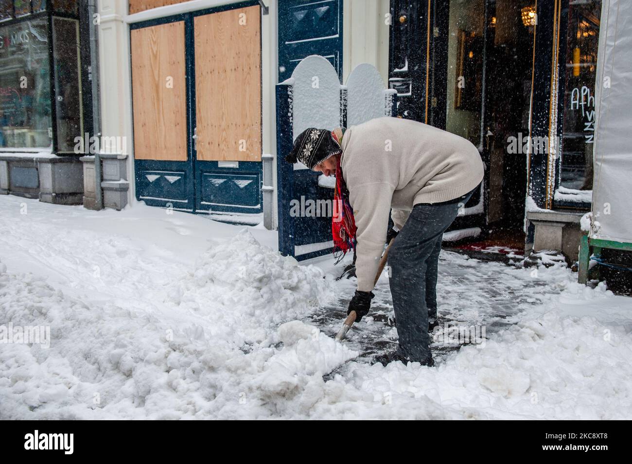 A man is clearing the snow from the front of his cafeteria, during the ...