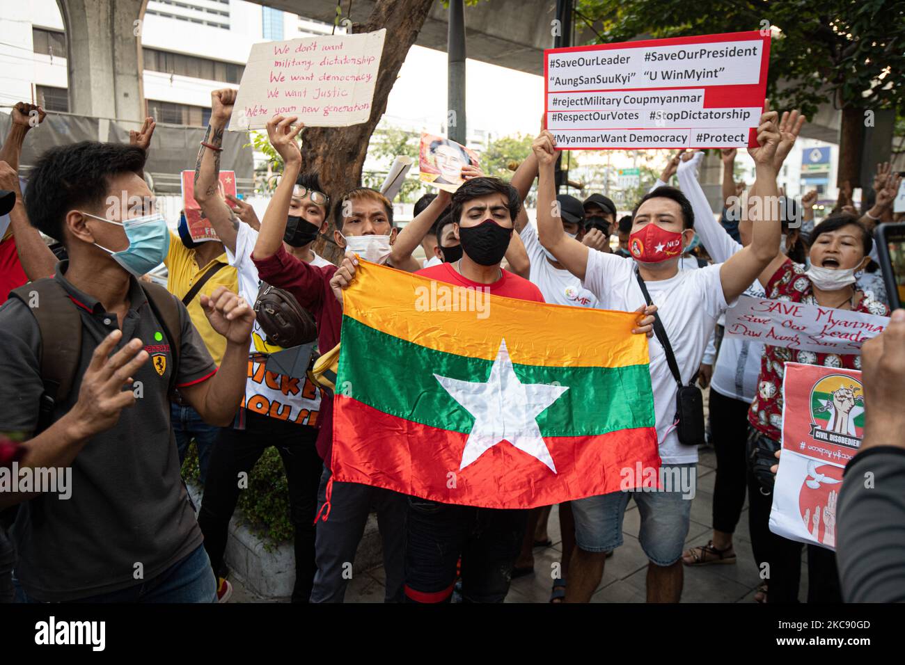 Myanmar residents in Bangkok hold up a Myanmar national flag while ...