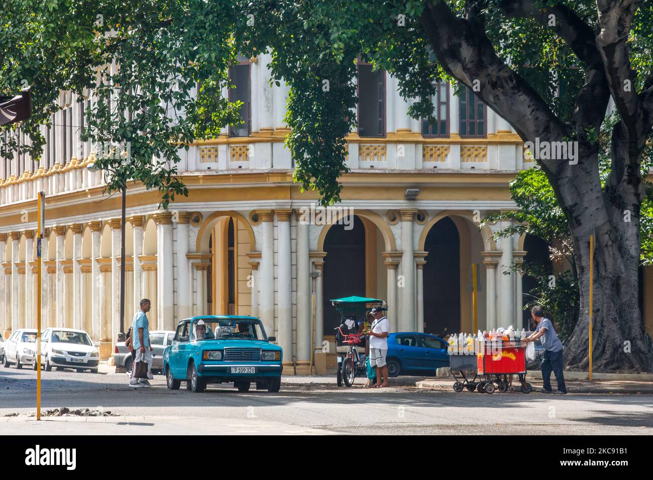 A Lada car drives in a downtown street where a Cuban man sells flavored ...