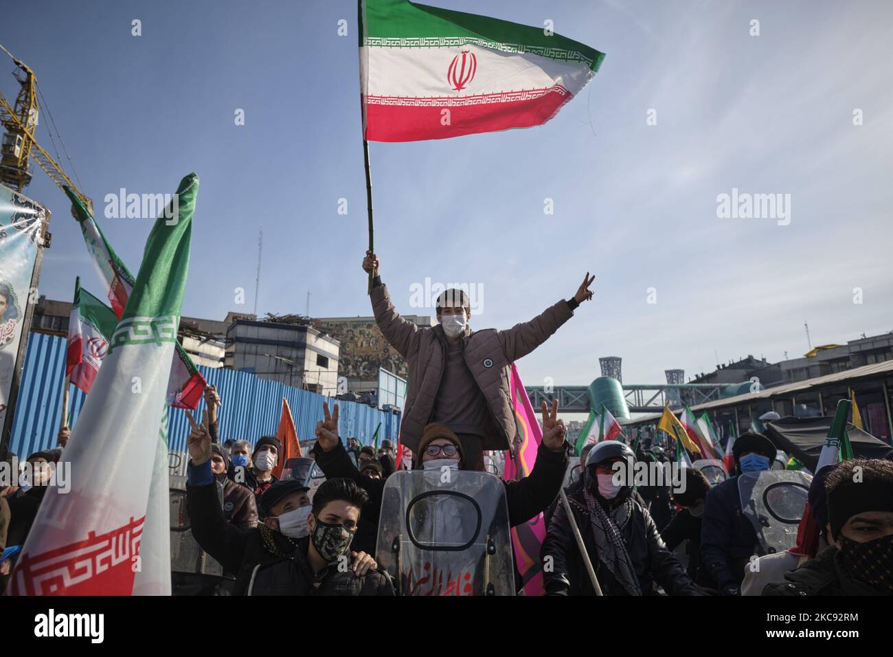 An Iranian man wearing a protective face mask waves an Iran flag and ...