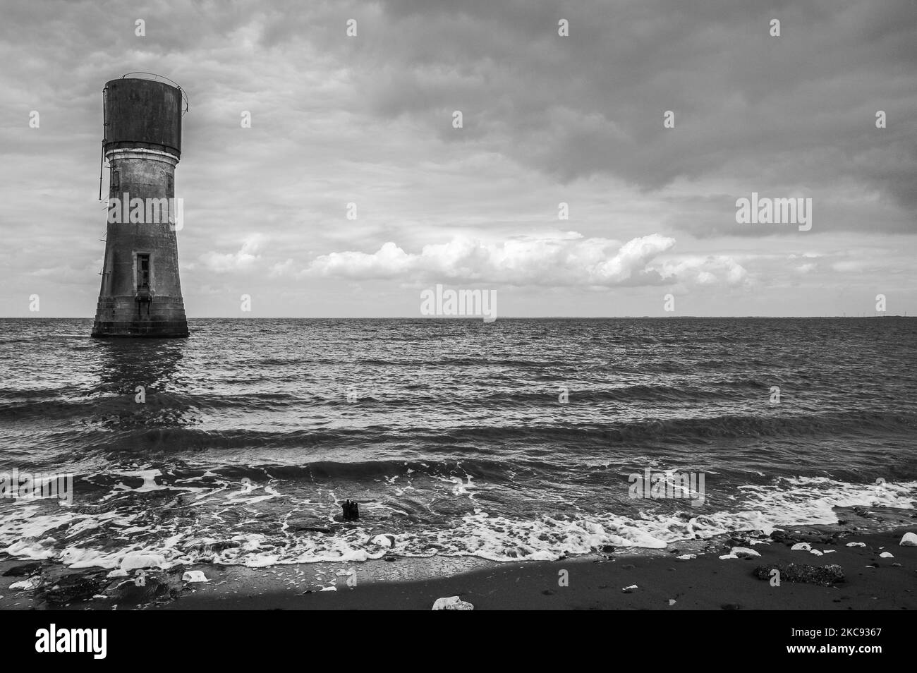 A grayscale of a Lighthouse on a sea with a cloudy sky background Stock ...
