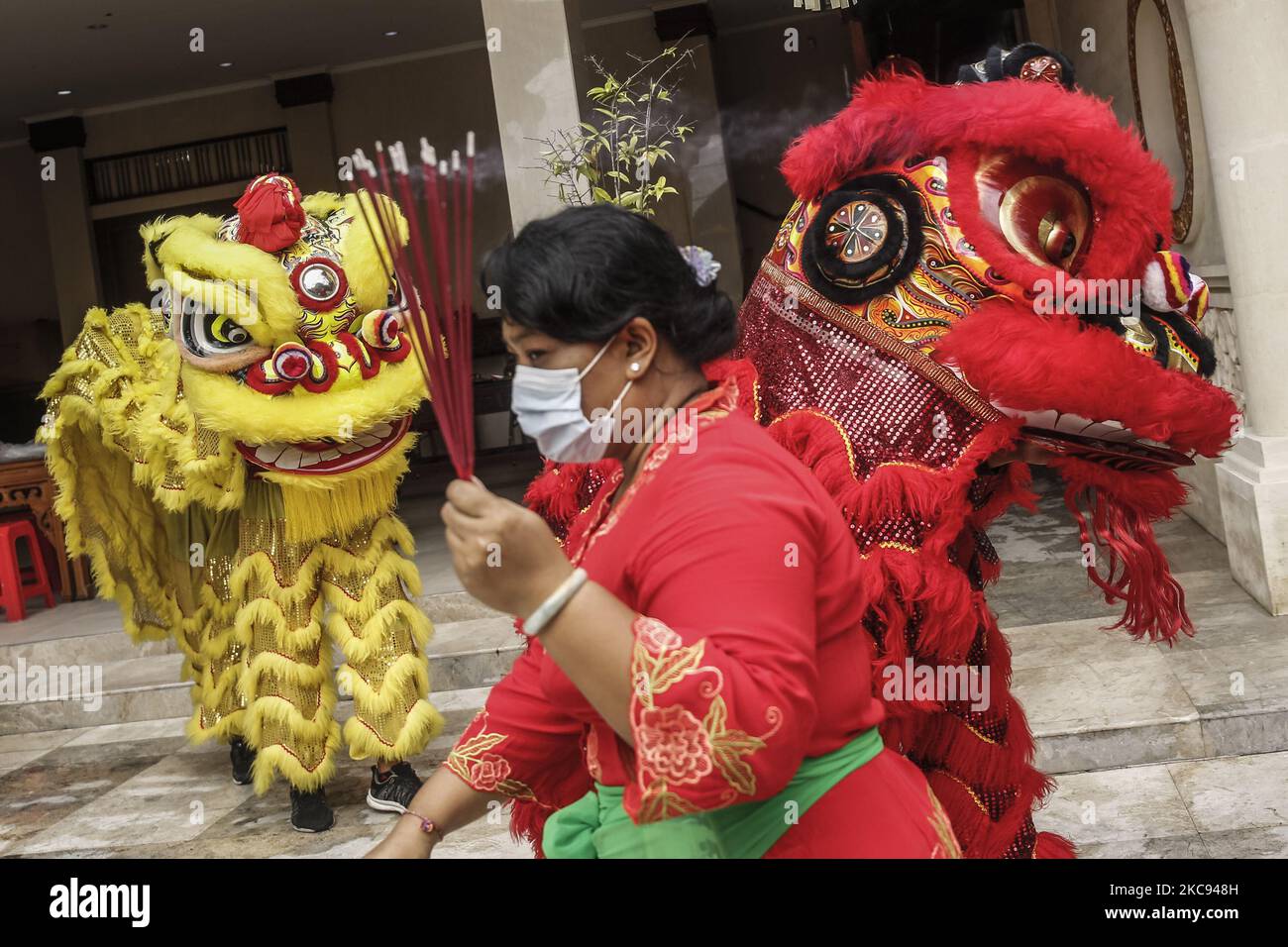 Woman wears protective mask while passing a couple of dragon dancers ...