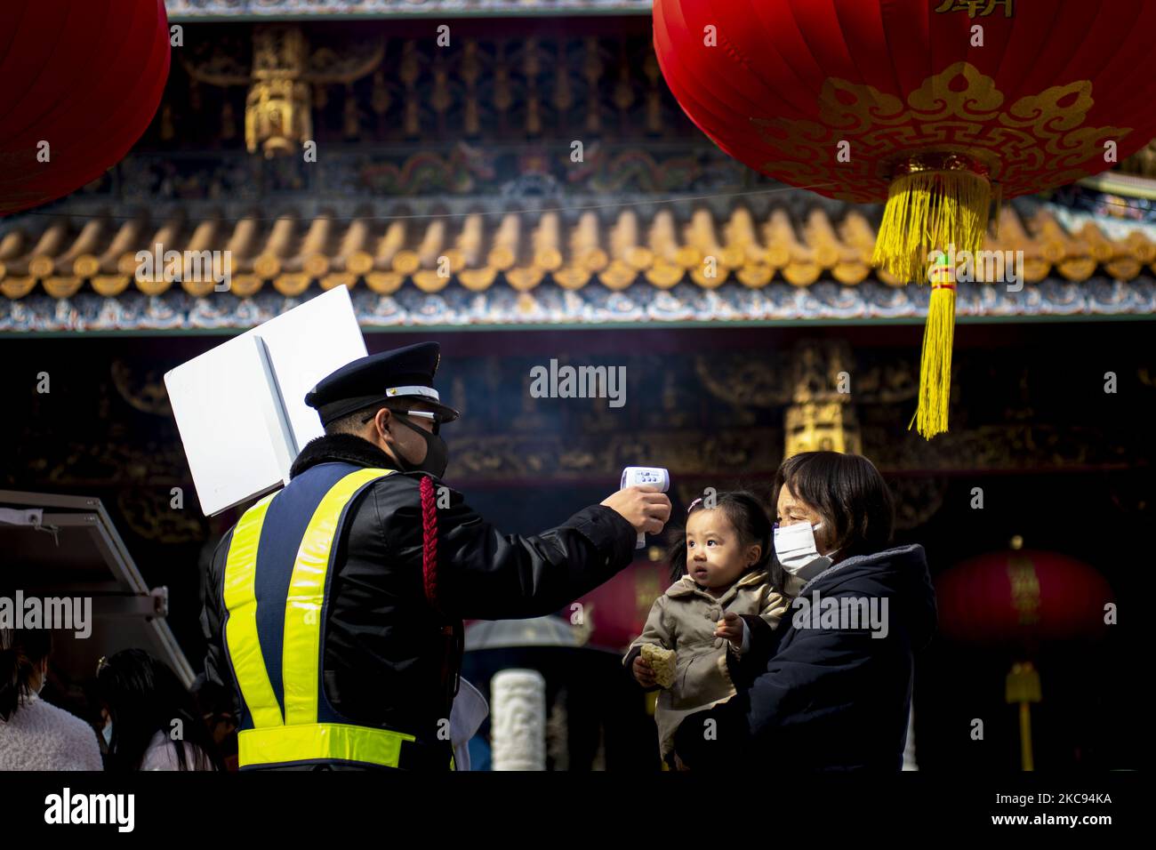 A guardsman measures the body temperature of a family before the enter ...