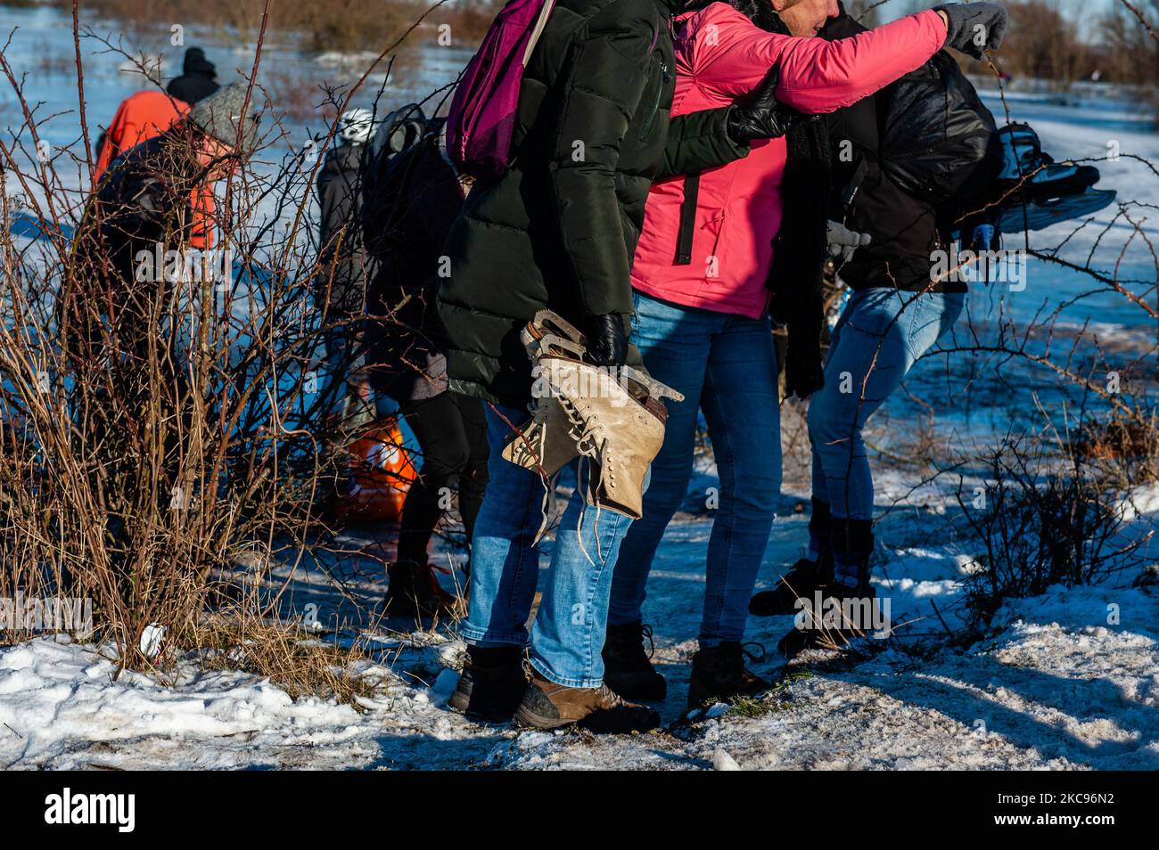 A group of people is carrying the ice skates, after skating on natural ...