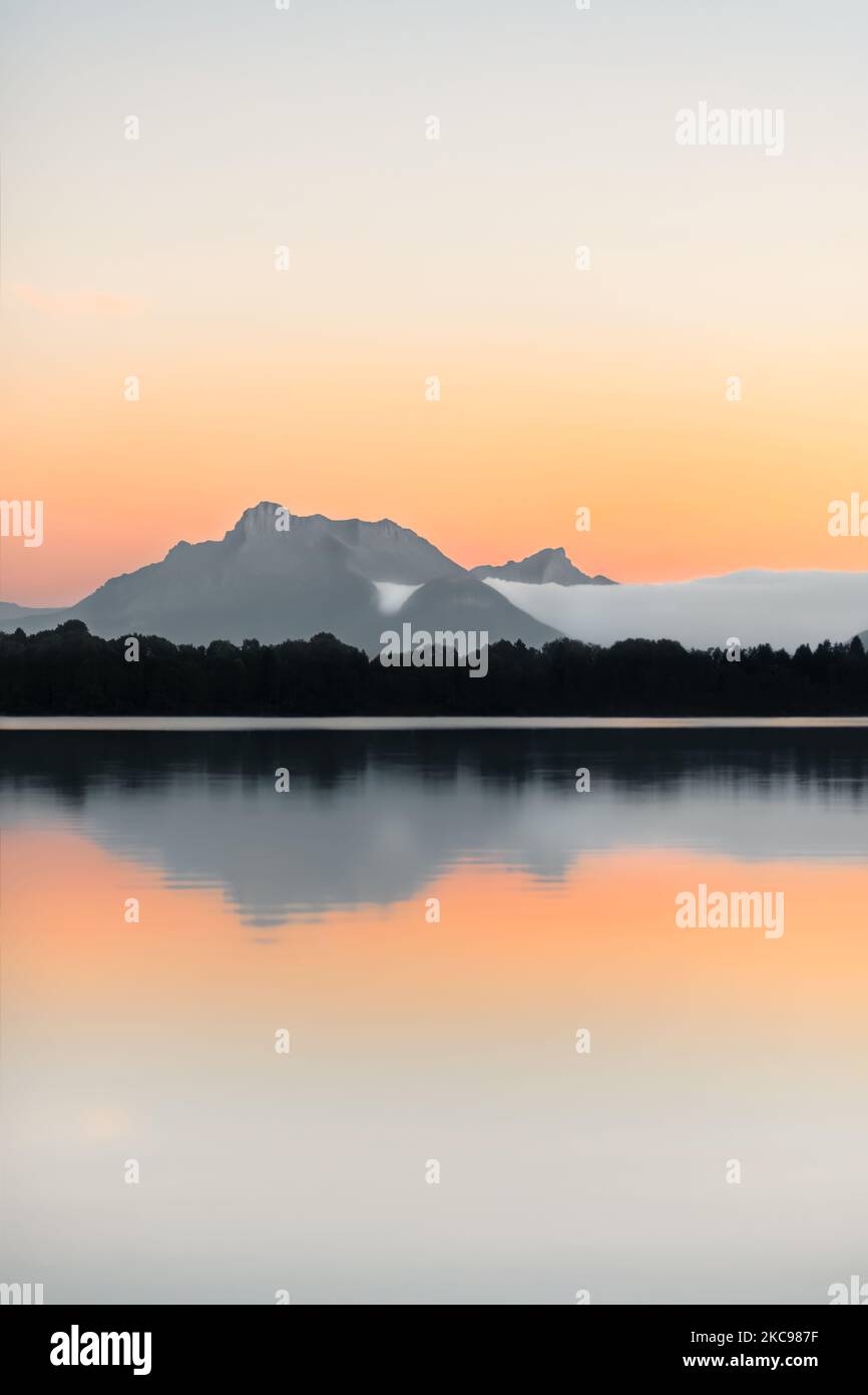 A mountain in the French Alps reflecting in a lake after sunset ...