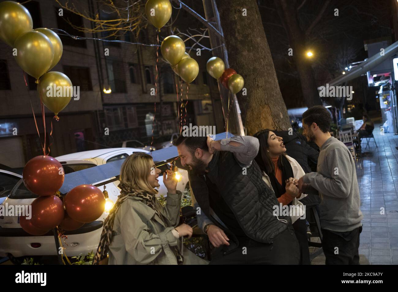 Iranian youth speak with each other out of a cafe that is decorated on ...