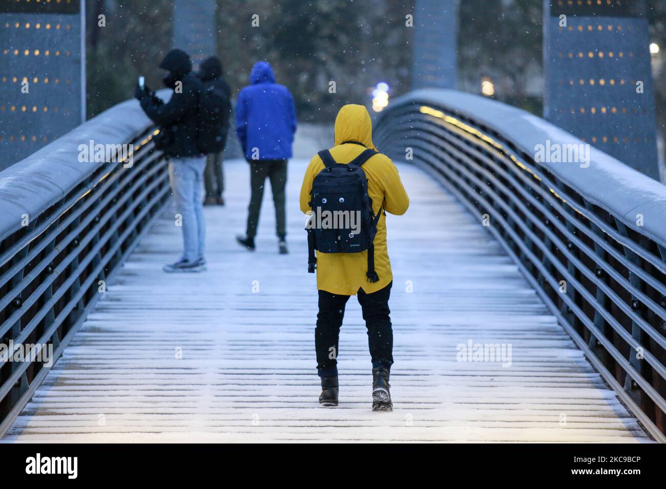 People gather to take photos of the snowy Houston skyline from a bridge ...
