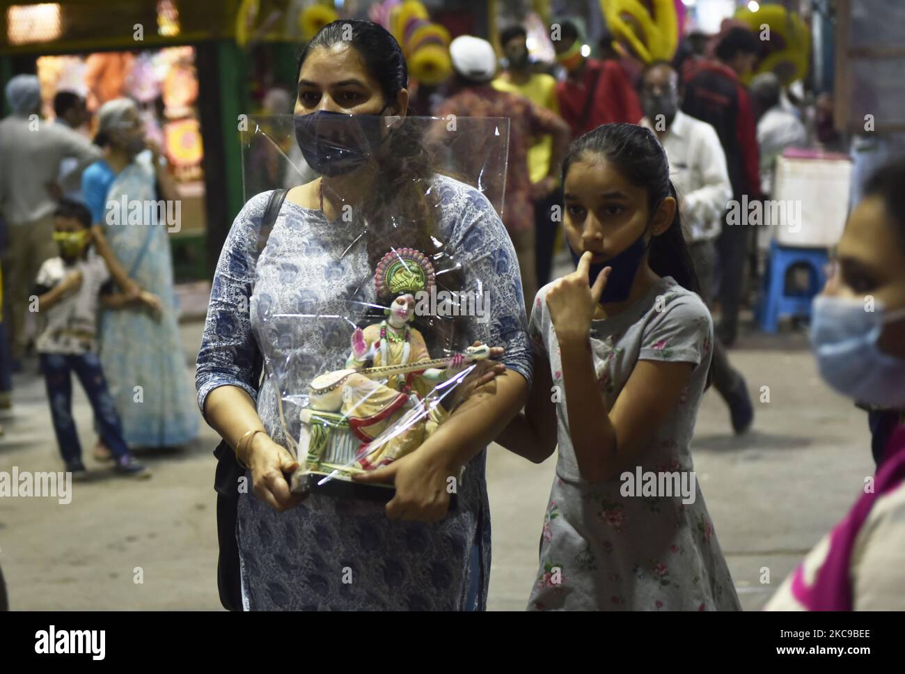 A woman carries a clay of Saraswati goddess covered with a plastic in ...