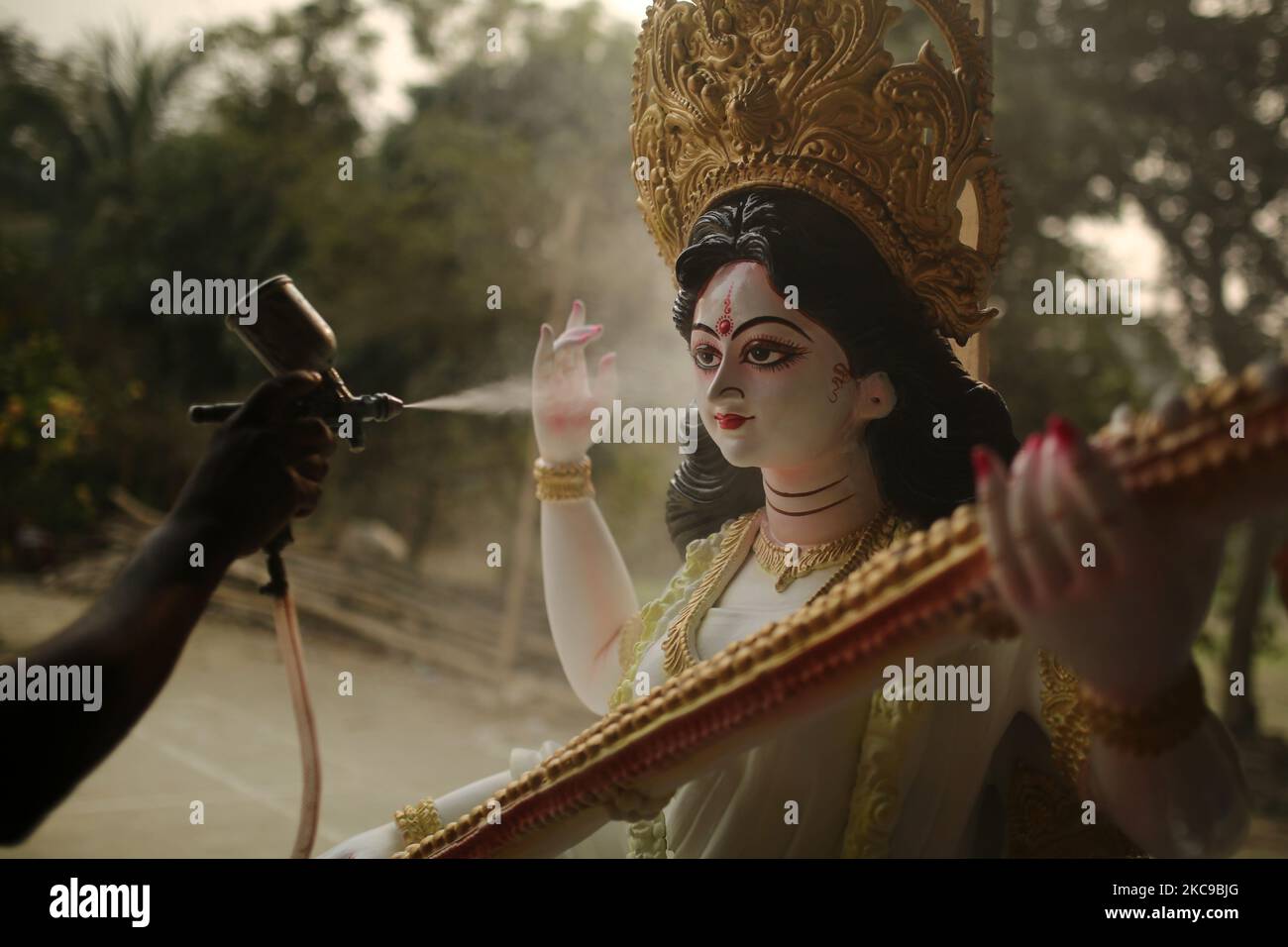 An artist gives a final retouch on a clay idol of goddess Saraswati at ...