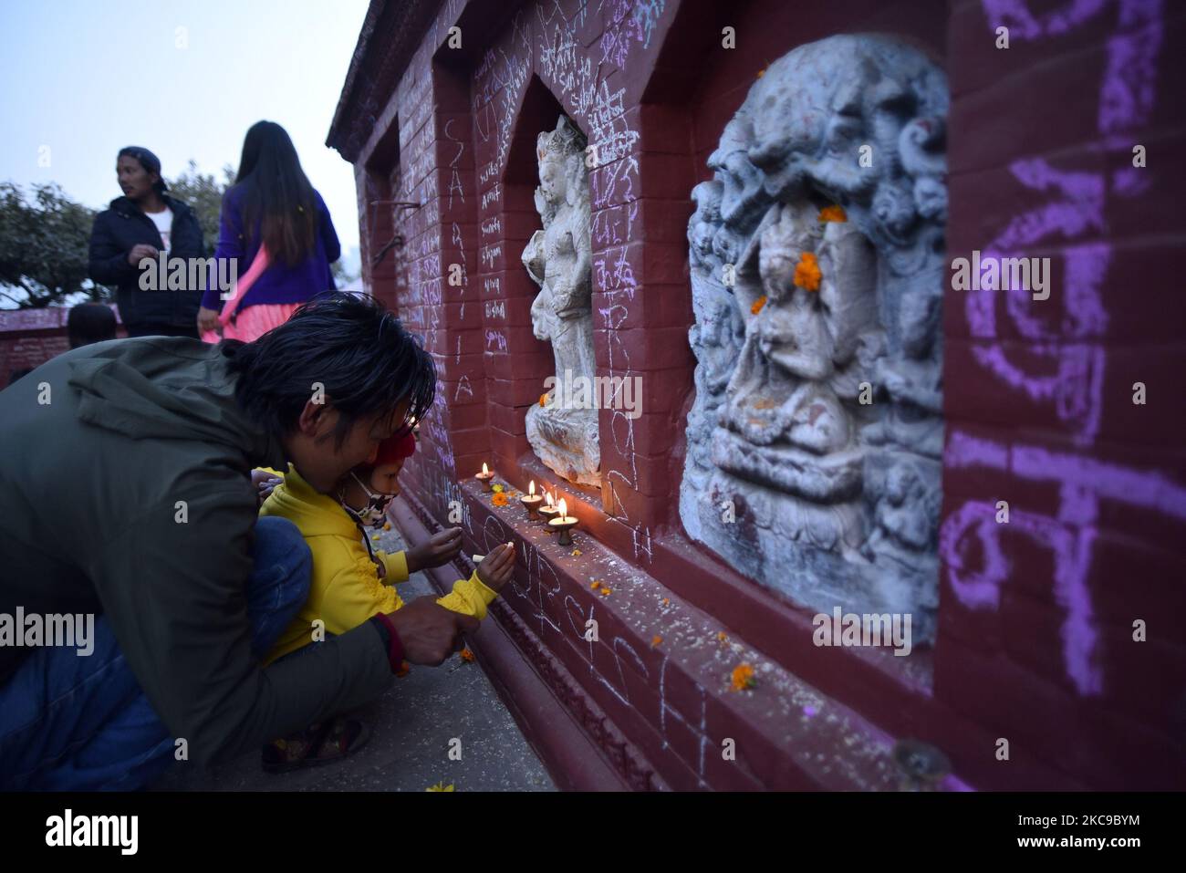 A father helps his child to write letters on the wall of Saraswati ...