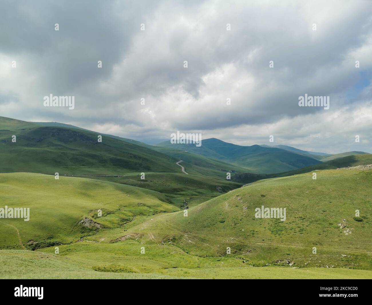 A beautiful view of a green landscape with hills under the cloudy sky ...