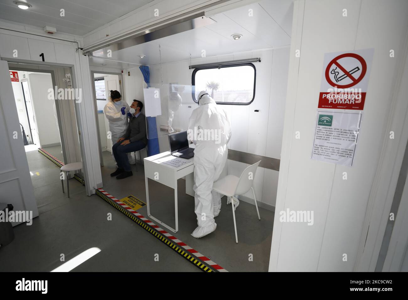 A health worker in a protective suit takes a sample from the nose of a ...