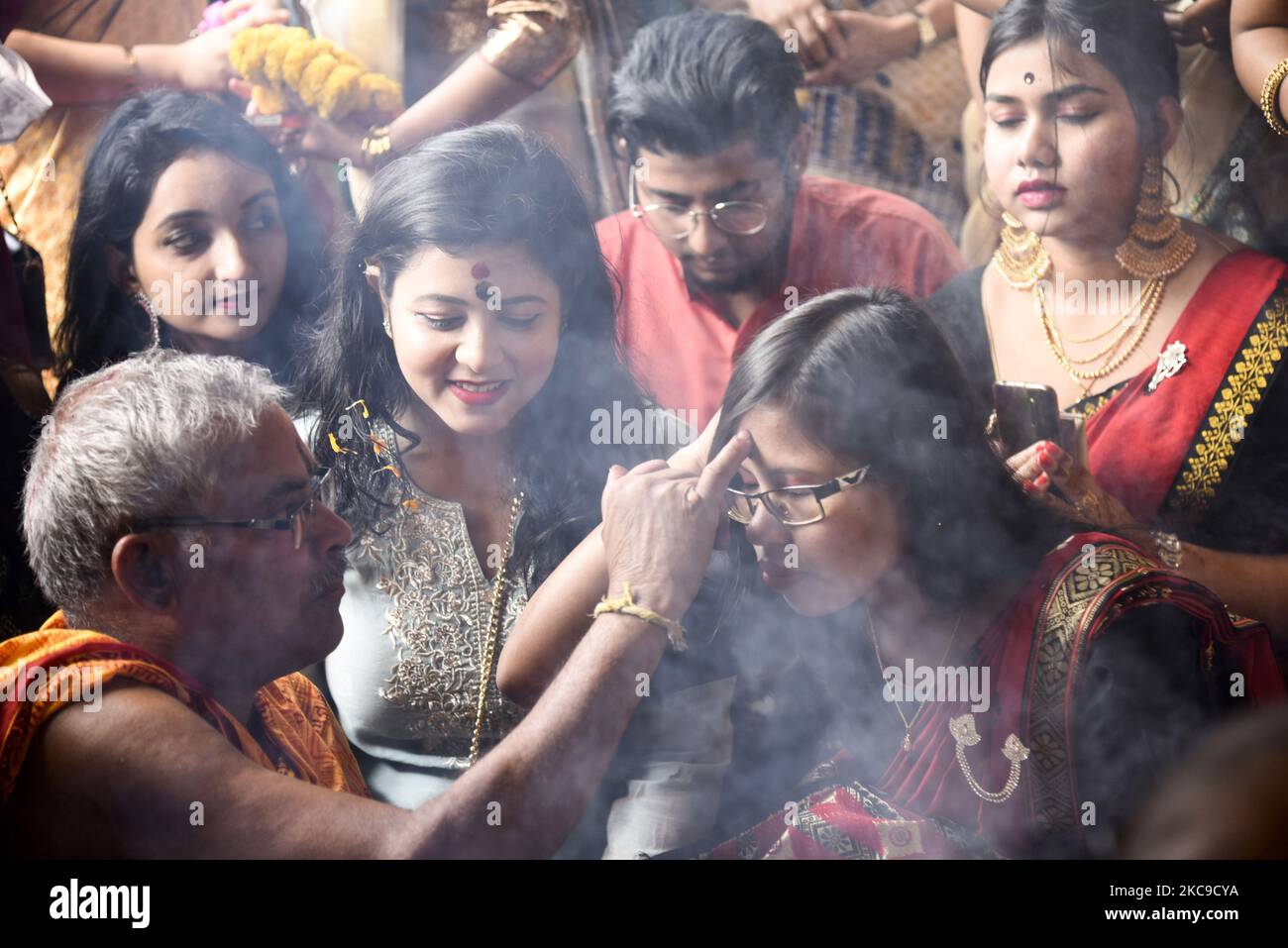 Devotees taking blessing from a priest as they offer prayer during ...