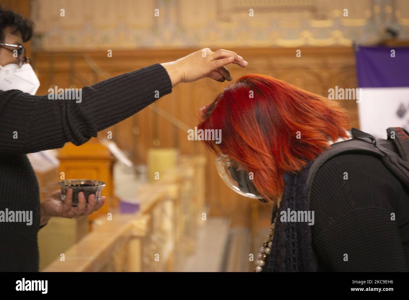 A church worker provides ash to a person's head as part of the Ash ...