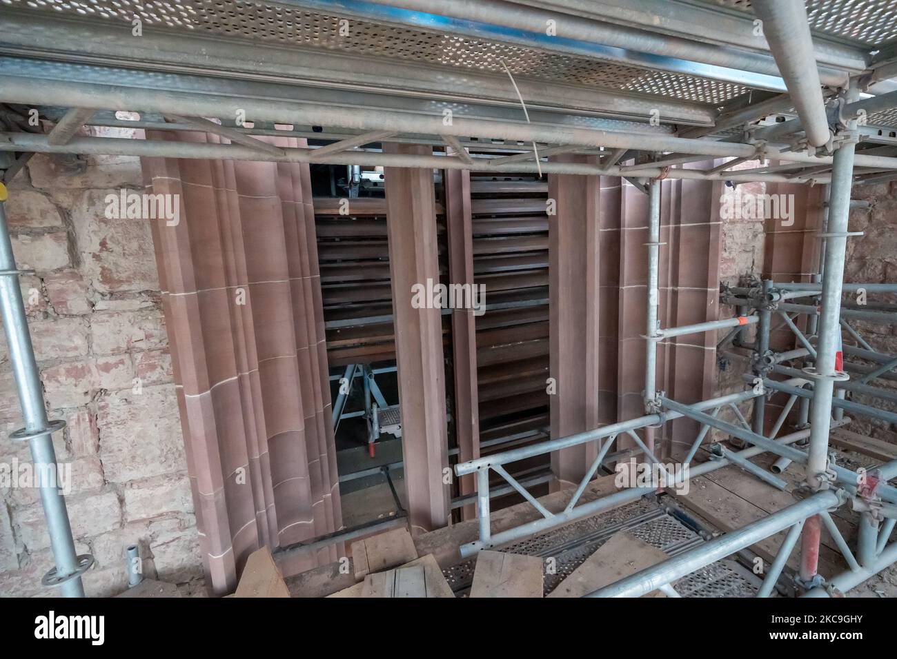 A construction site with scaffolding against brick and concrete walls ...