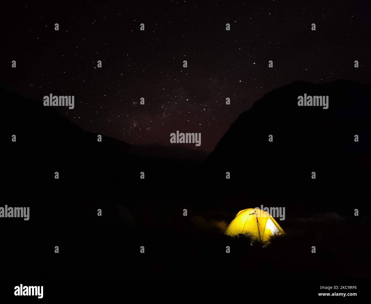 Orange glowing tent in New Zealand with the milky way and the southern ...