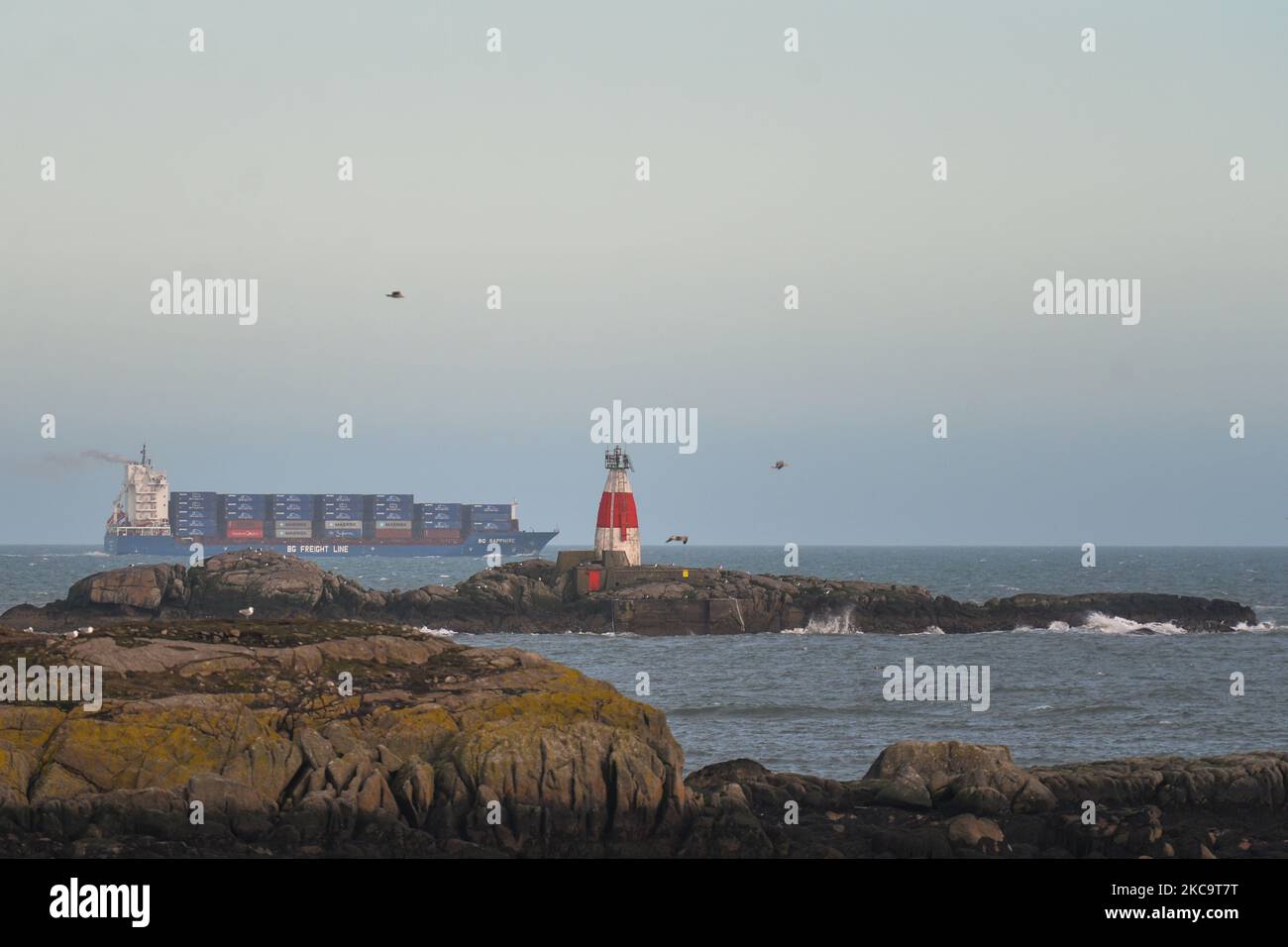 A container ship sails past a lighthouse as it departs Dublin Bay in ...