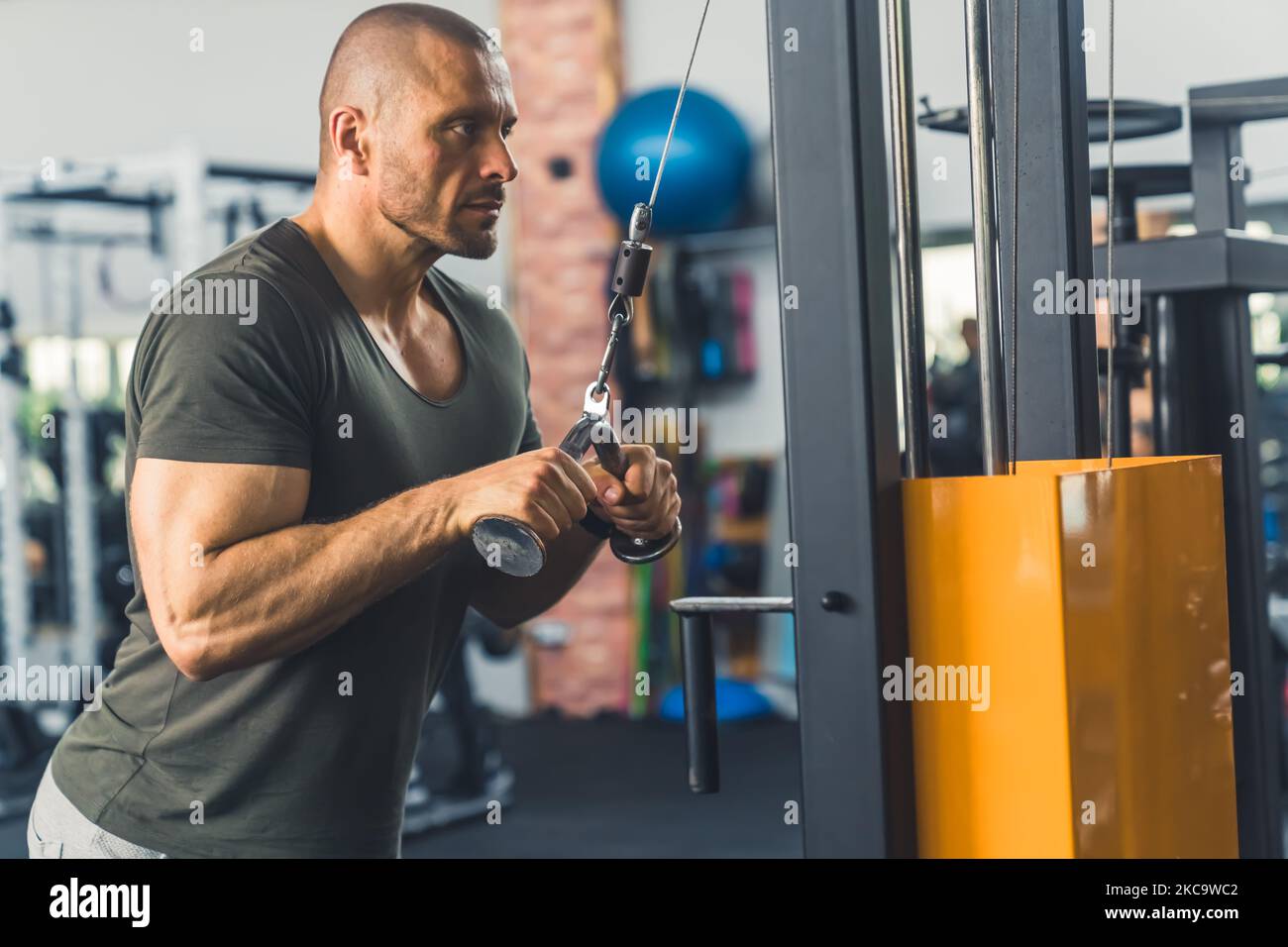 Private male caucasian trainer doing arm exercises at gym using ...