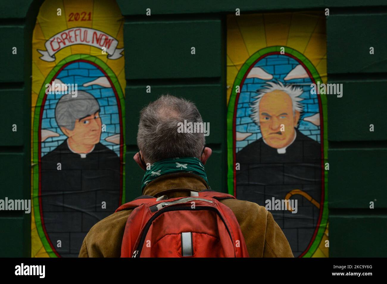 A man looks at images of Father Ted and Father Jack seen in windows of ...