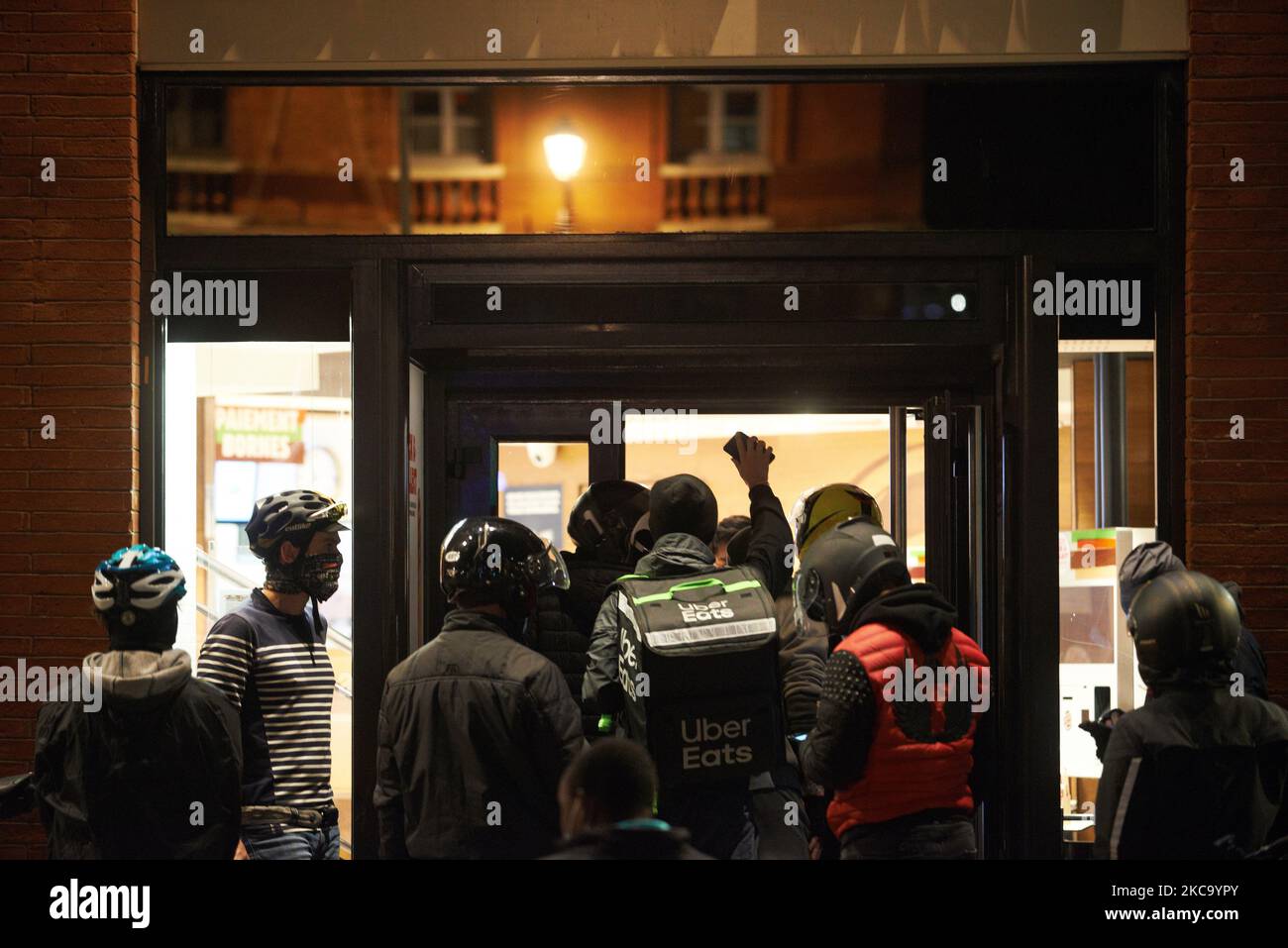 Delivery workers gesture in front of restaurant to obtain their orders ...